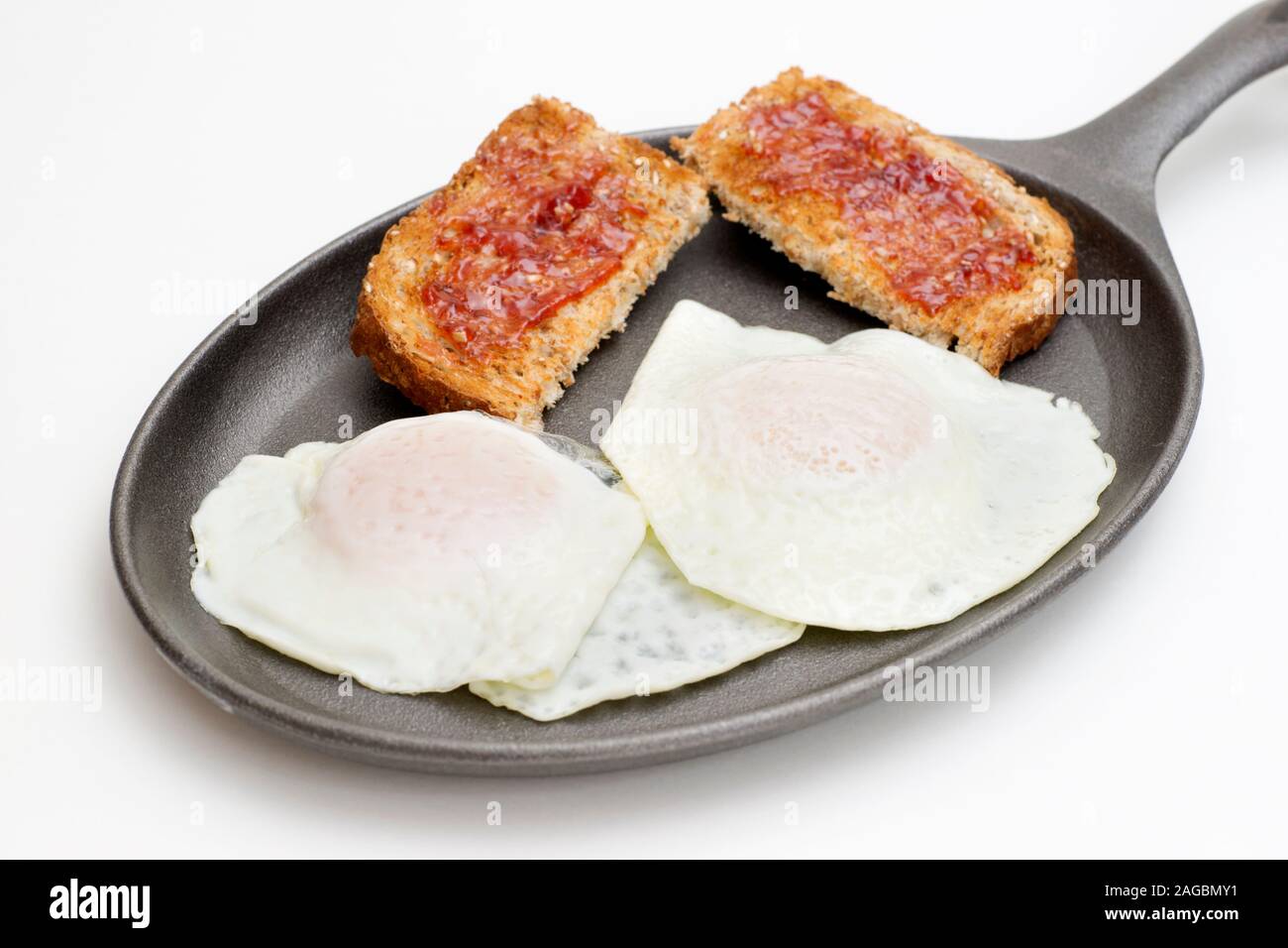Fried eggs and toast with jelly in elongated cast iron frying pan Stock ...