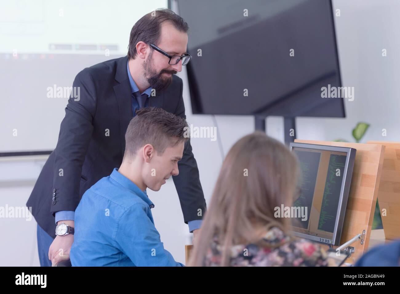 Group of students study with professor in modern school computer lab ...