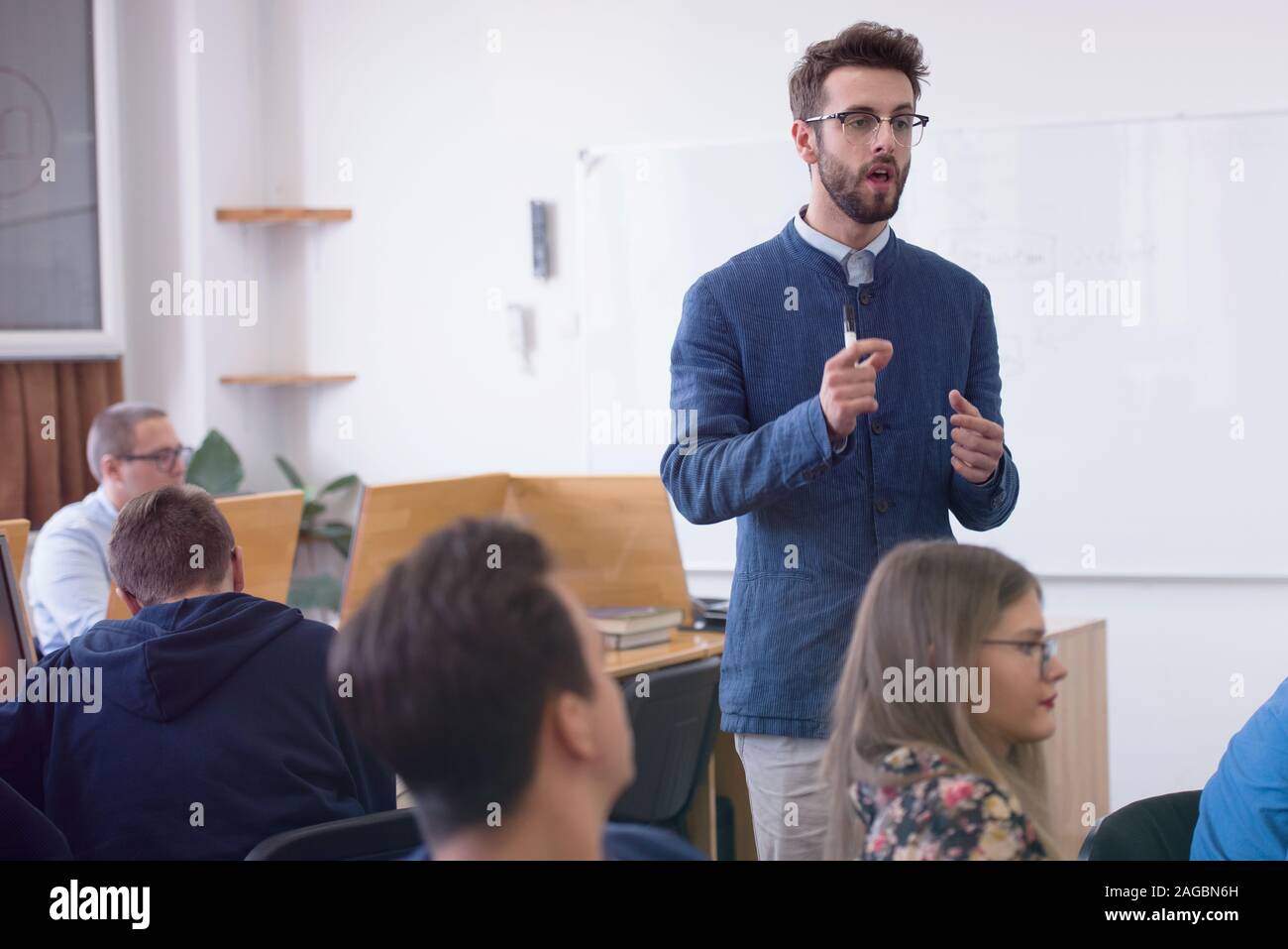 Group of students study with professor in modern school classroom. Male ...