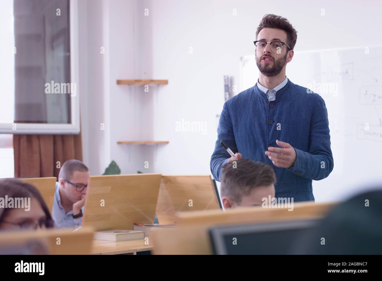 Group of students study with professor in modern school classroom. Male ...