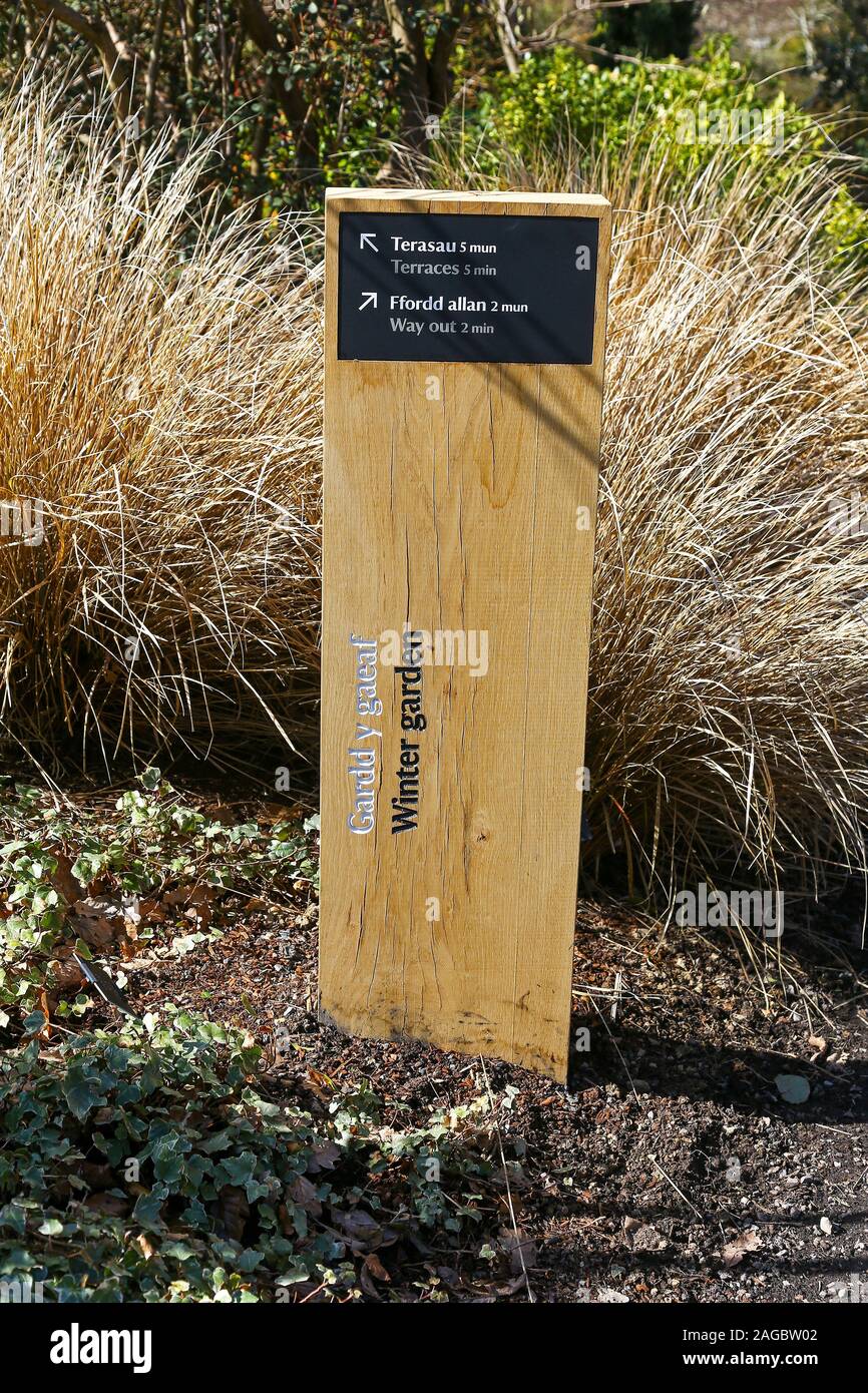 A wooden sign post for the winter garden (in English and Welsh) at ...