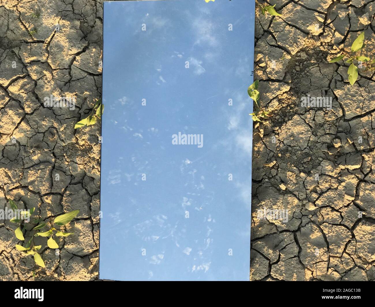 Overhead shot of clouds reflecting in the mirror on a cracked ground ...