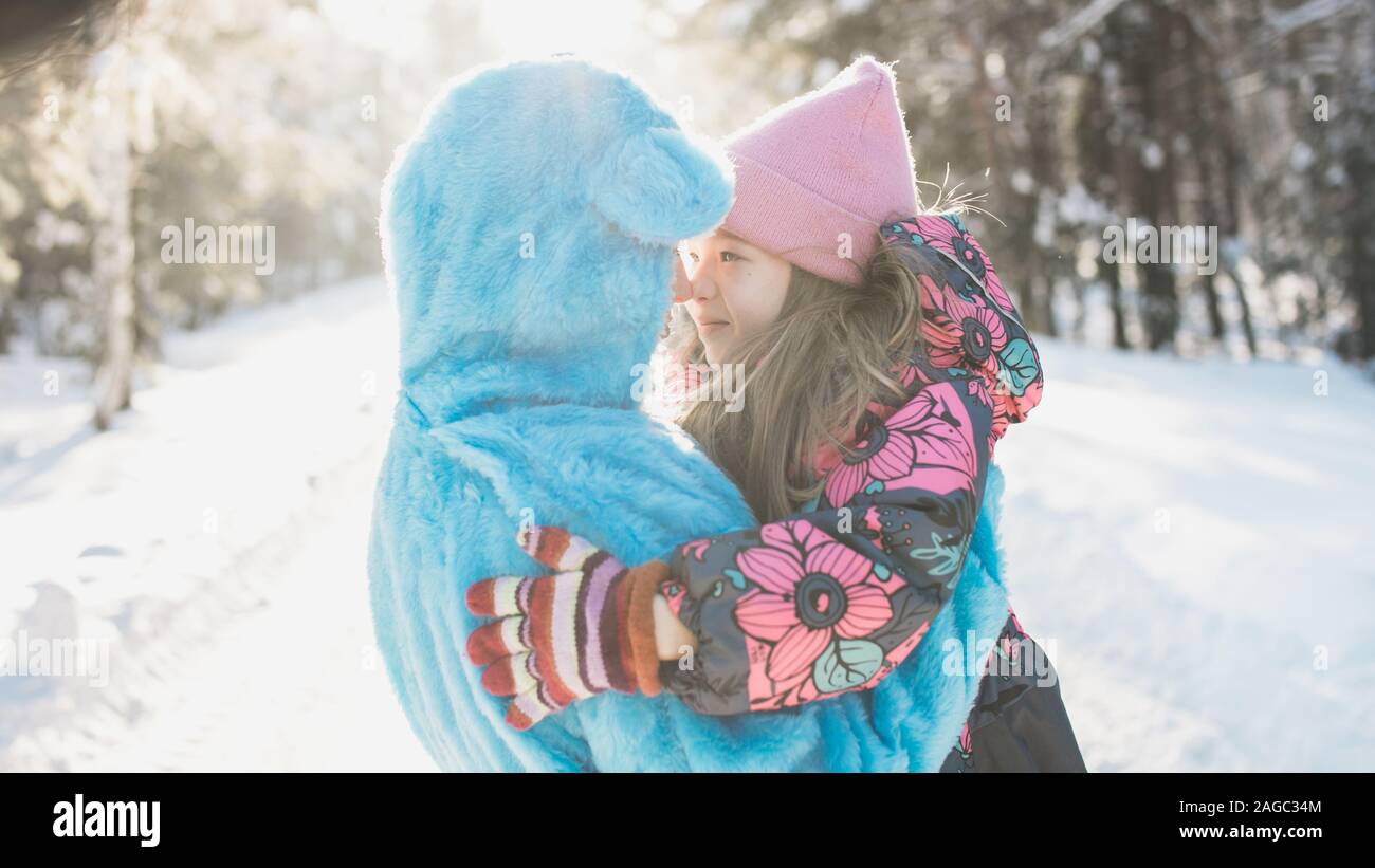 Closeup shot of a female in fluffy blue costume hugging a little girl ...