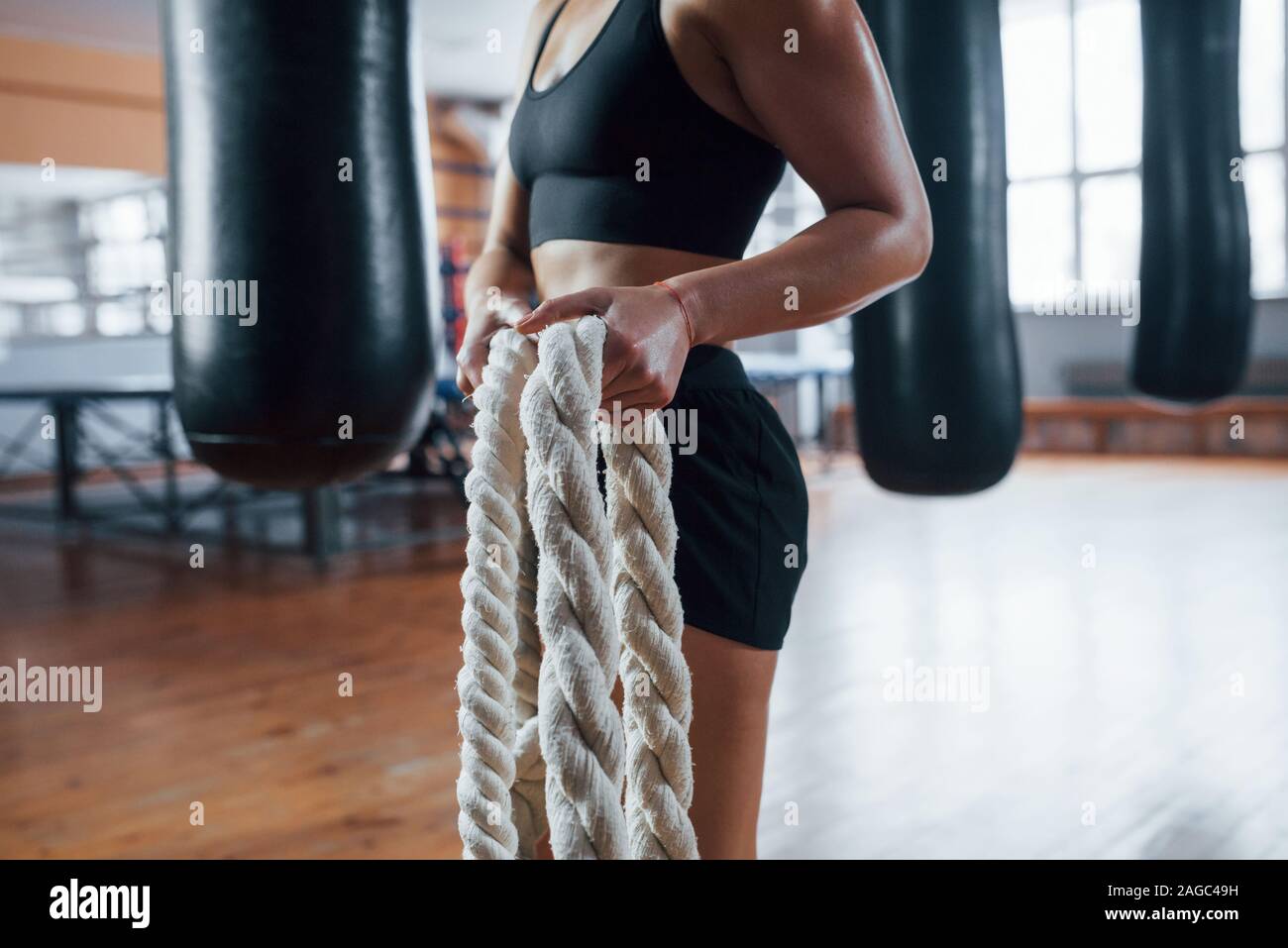 In black wear. Blonde sport woman have exercise with ropes in the gym ...
