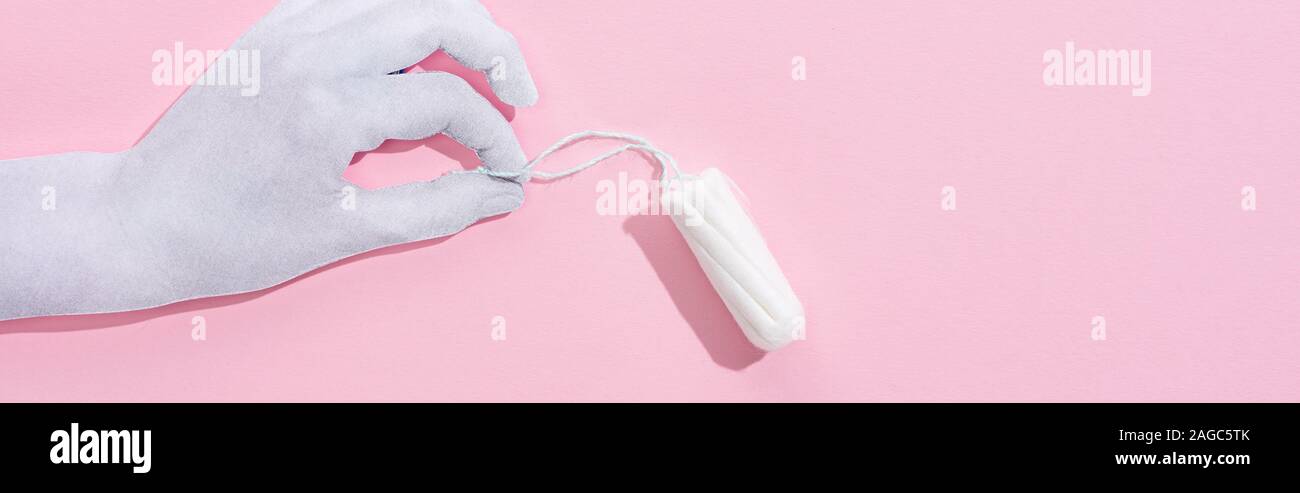 top view of white paper hand holding cotton tampon on pink background ...