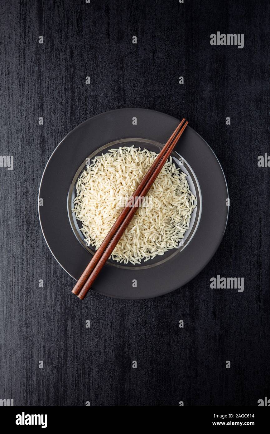 Uncooked indian long rice on plate and chopsticks Stock Photo - Alamy