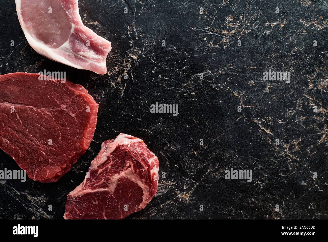 top view of raw beef and pork parts on black marble surface Stock Photo ...