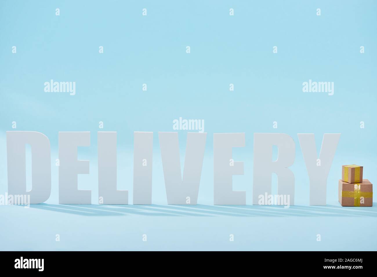 white delivery word near closed cardboard boxes on blue background with ...