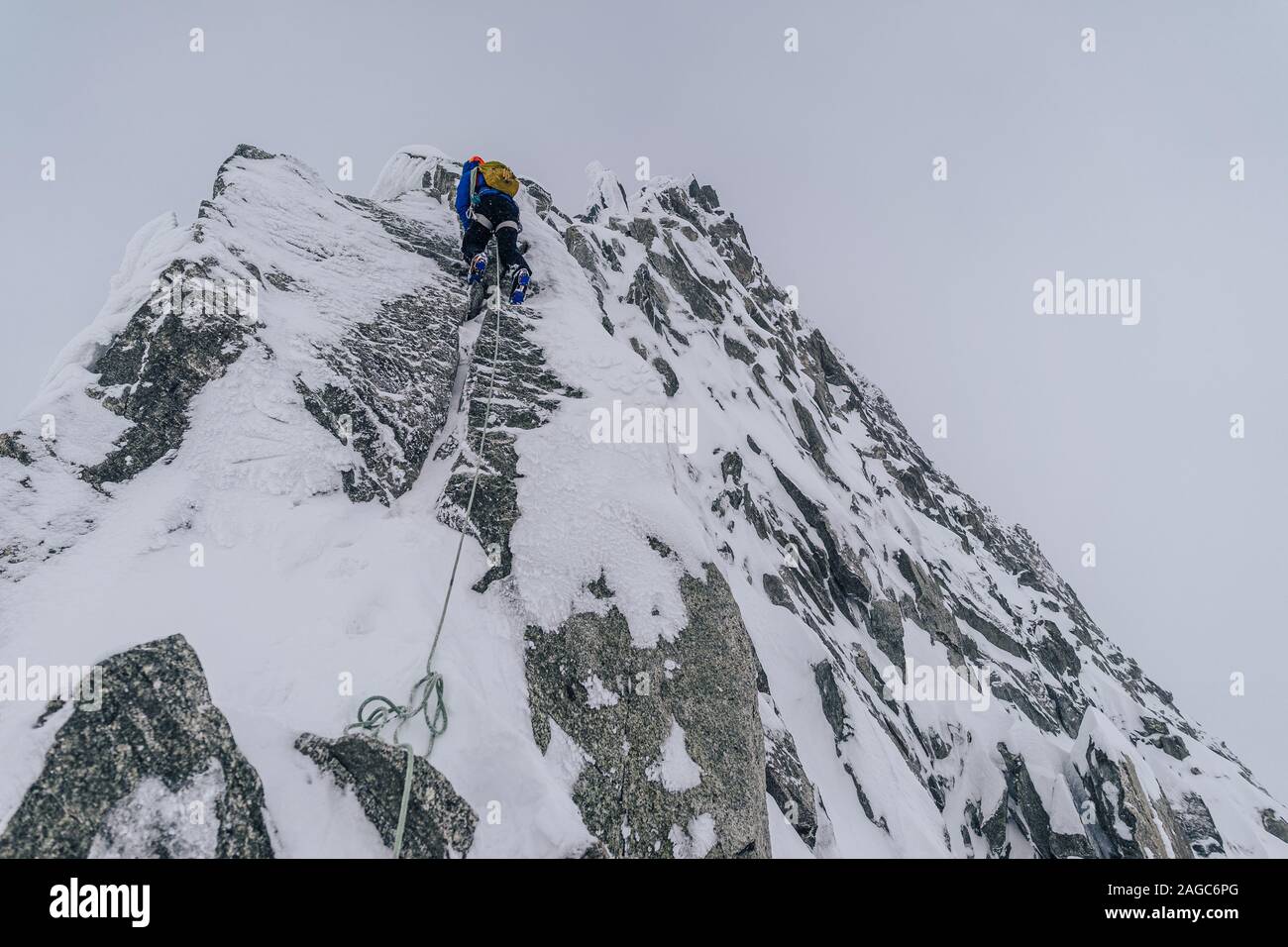 An alpinist climbing an alpine ridge in winter extreme conditions ...