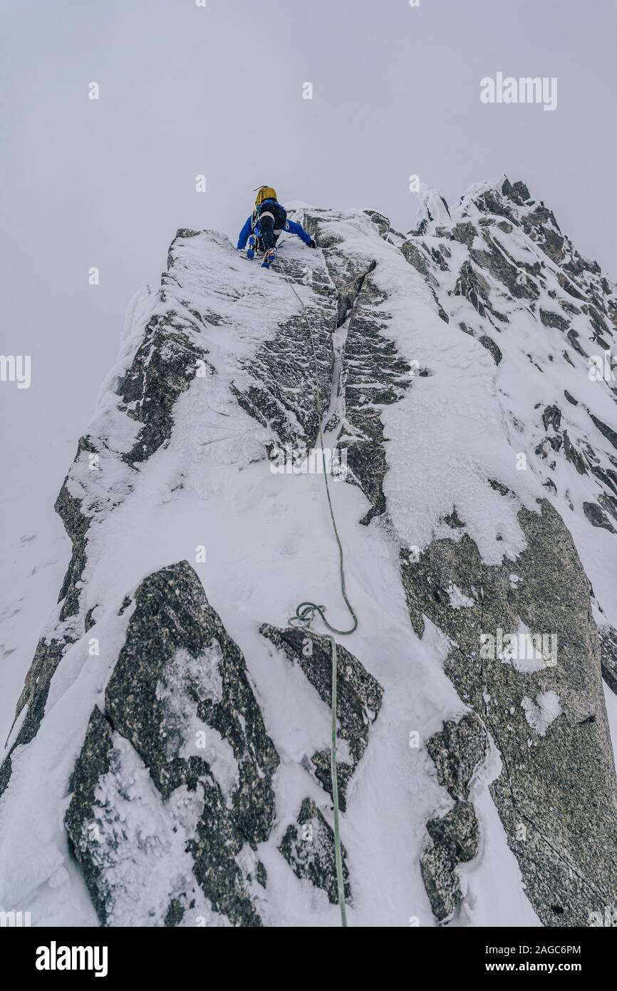 An alpinist climbing an alpine ridge in winter extreme conditions ...
