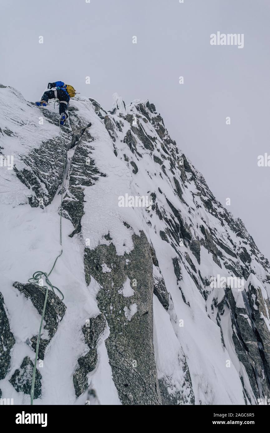 An alpinist climbing an alpine ridge in winter extreme conditions ...