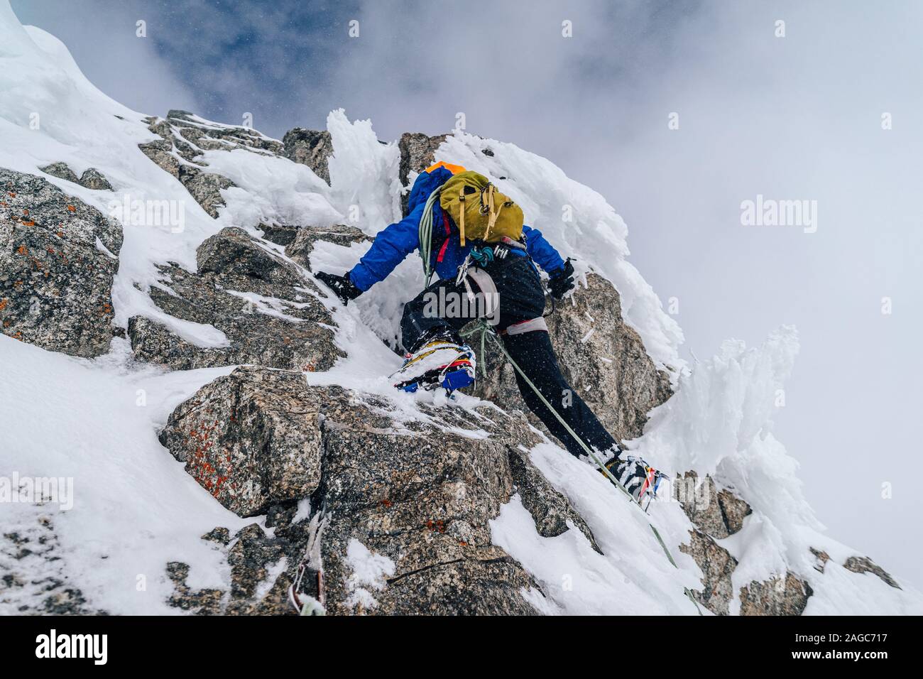 An alpinist climbing an alpine ridge in winter extreme conditions ...