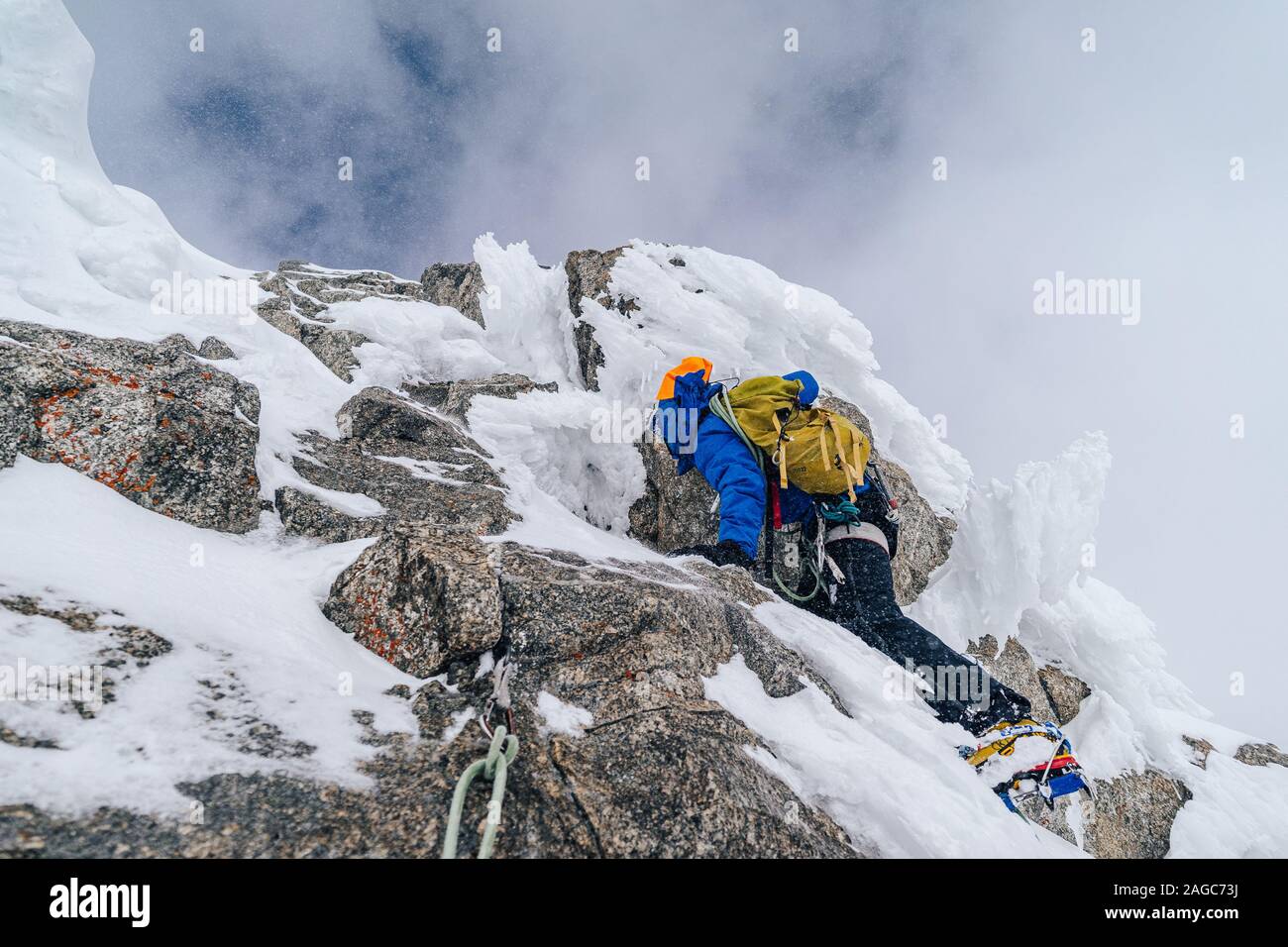 An alpinist climbing an alpine ridge in winter extreme conditions ...