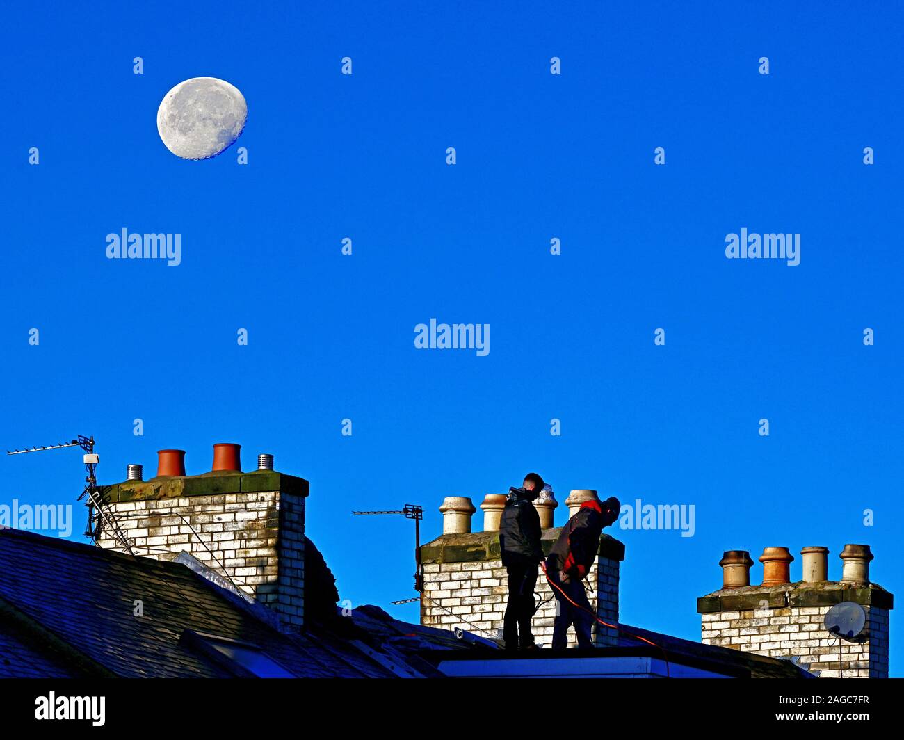 Rooftop repairs and full moon Stock Photo - Alamy