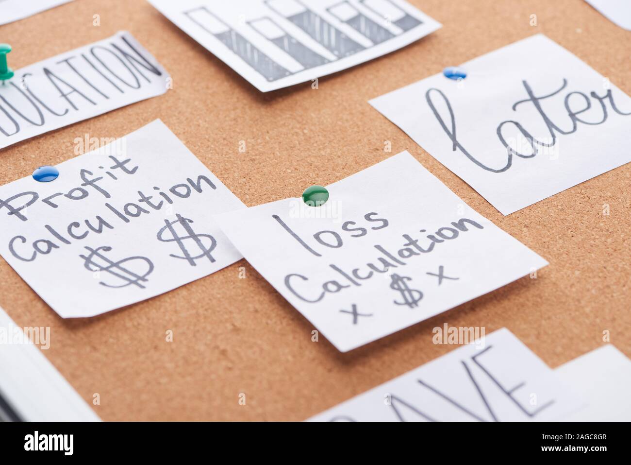 paper cards with profit and loss calculations notes pinned on cork ...