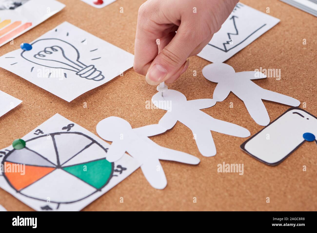 cropped view of woman pinning paper craft decoration on cork board ...