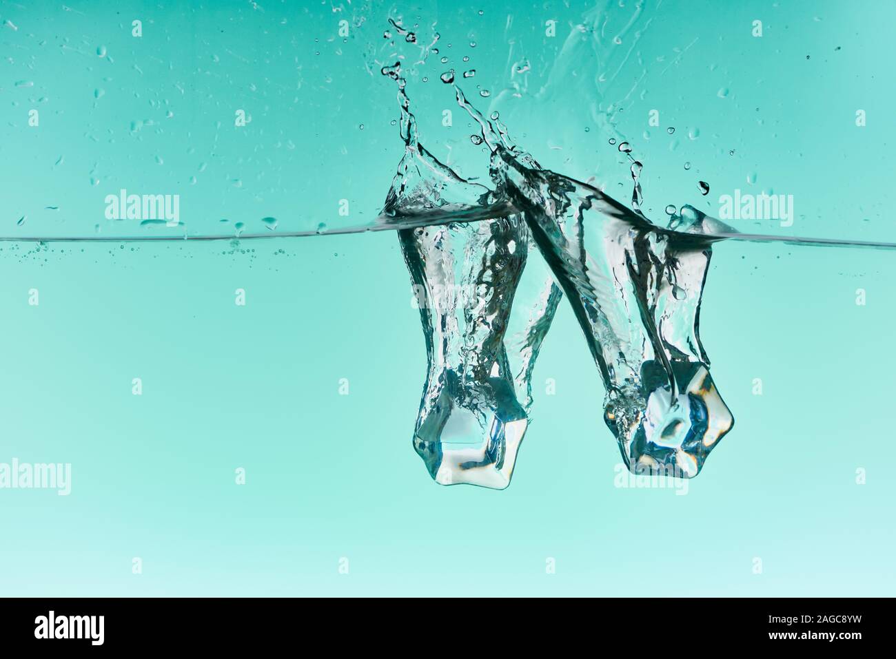 ice cubes falling in water with splash on turquoise background Stock ...