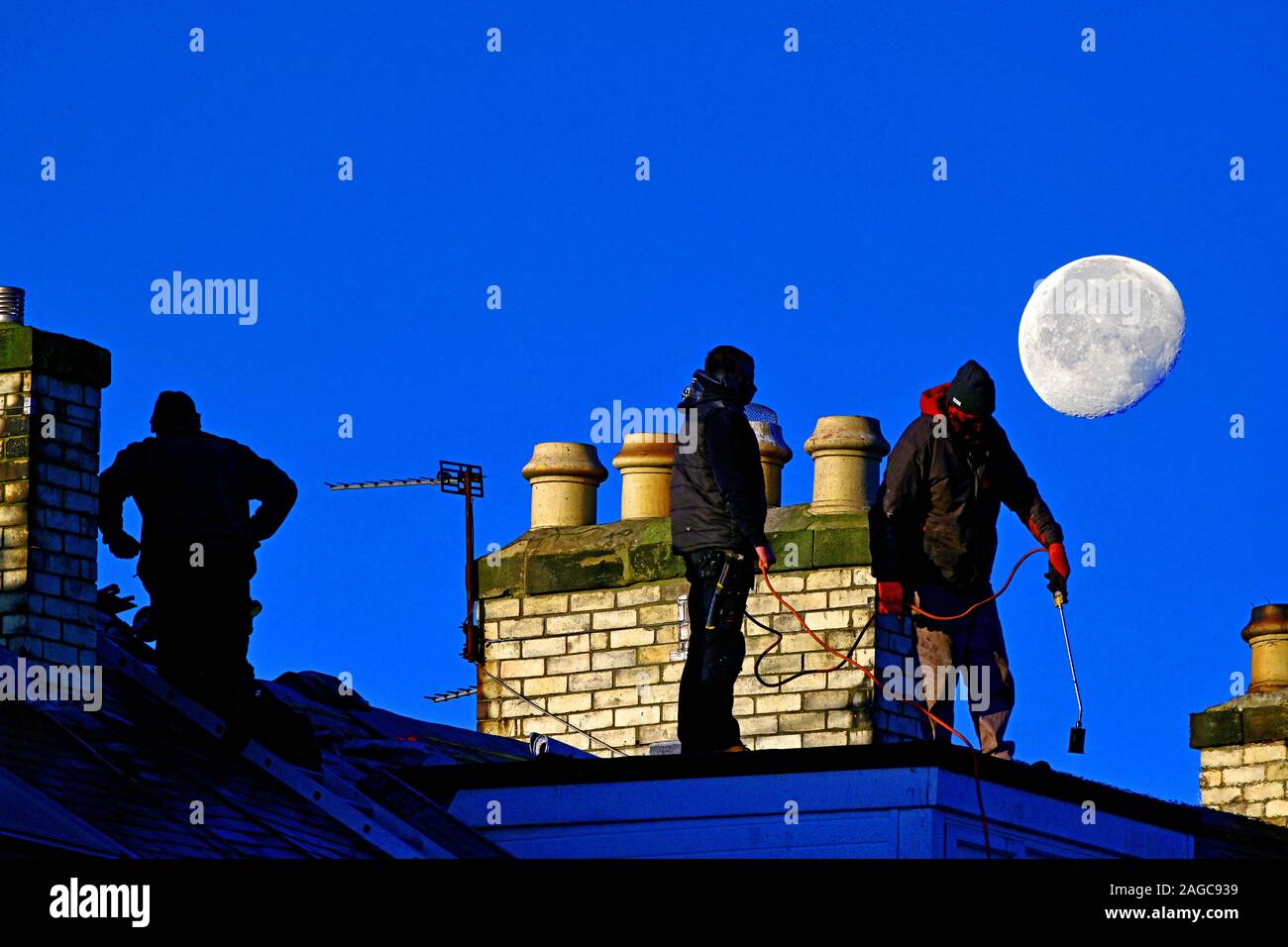Rooftop repairs and full moon Stock Photo - Alamy