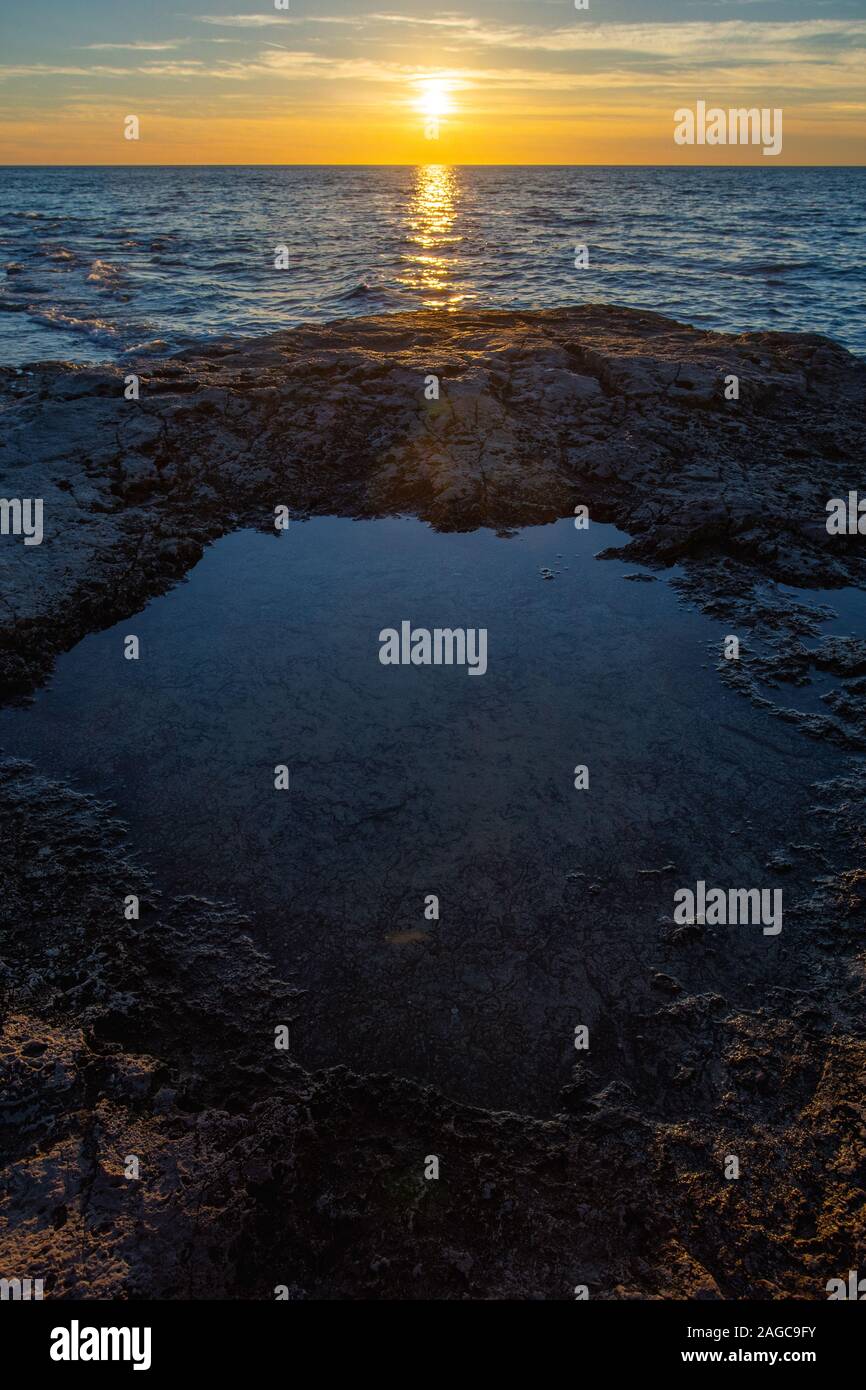 Vertical shot of the sunset over rock formations in the Adriatic sea in ...