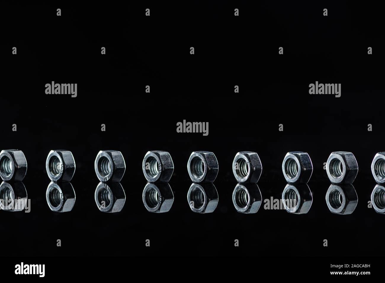 horizontal row of metal nuts isolated on black Stock Photo - Alamy