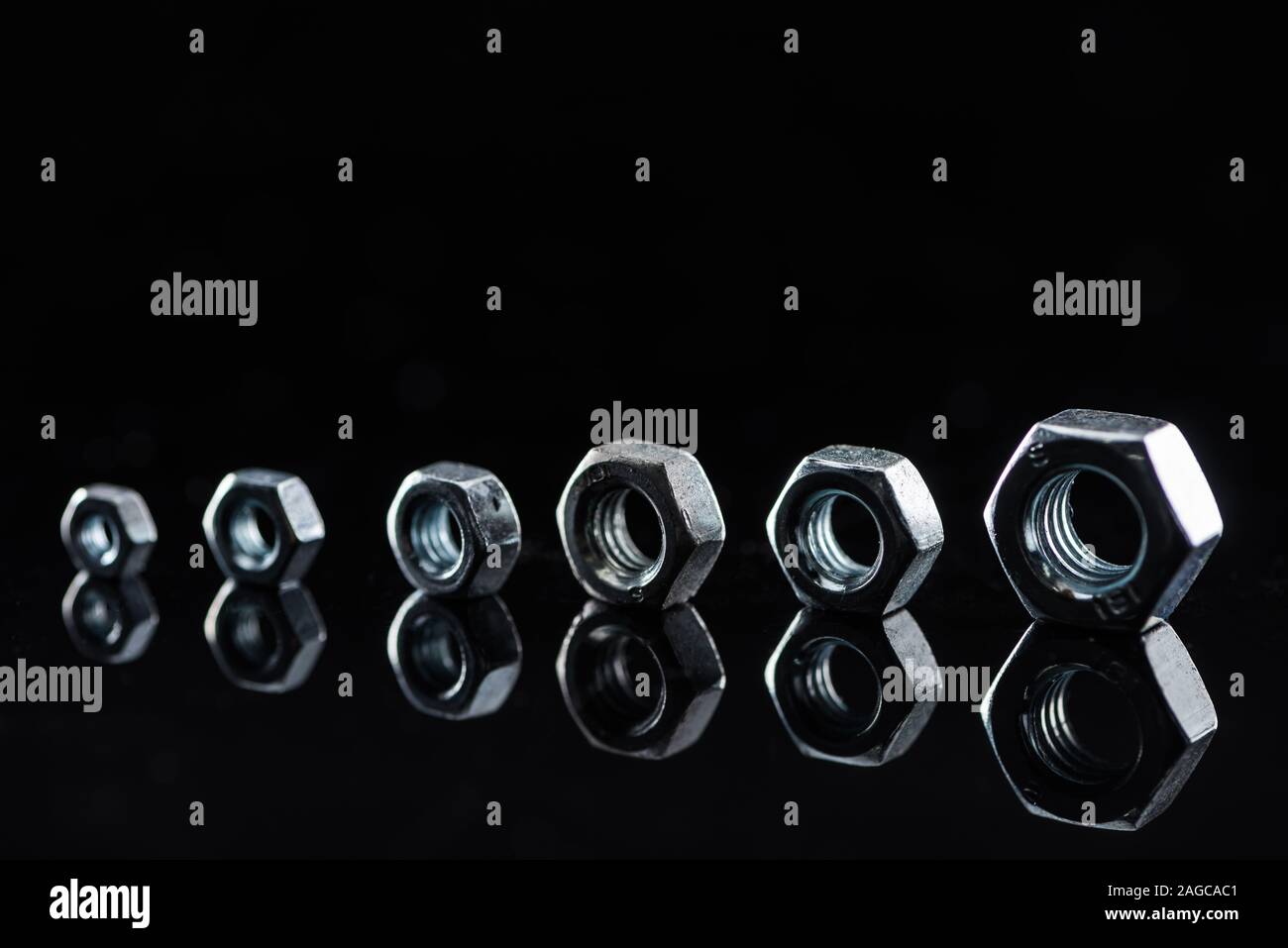 metal nuts of different sizes isolated on black Stock Photo - Alamy