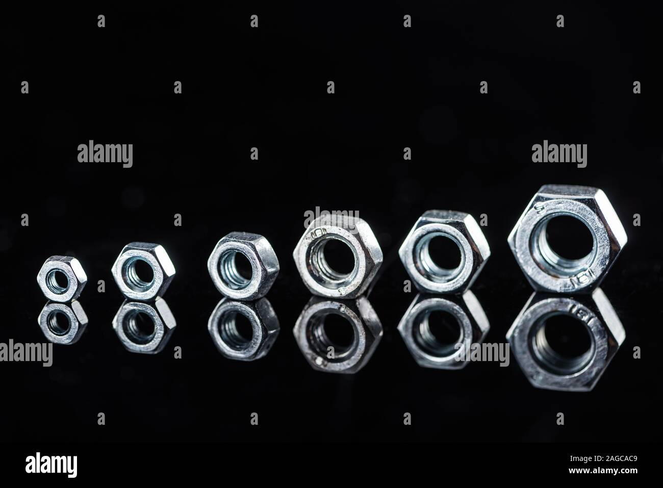 row of shiny metallic nuts isolated on black Stock Photo - Alamy