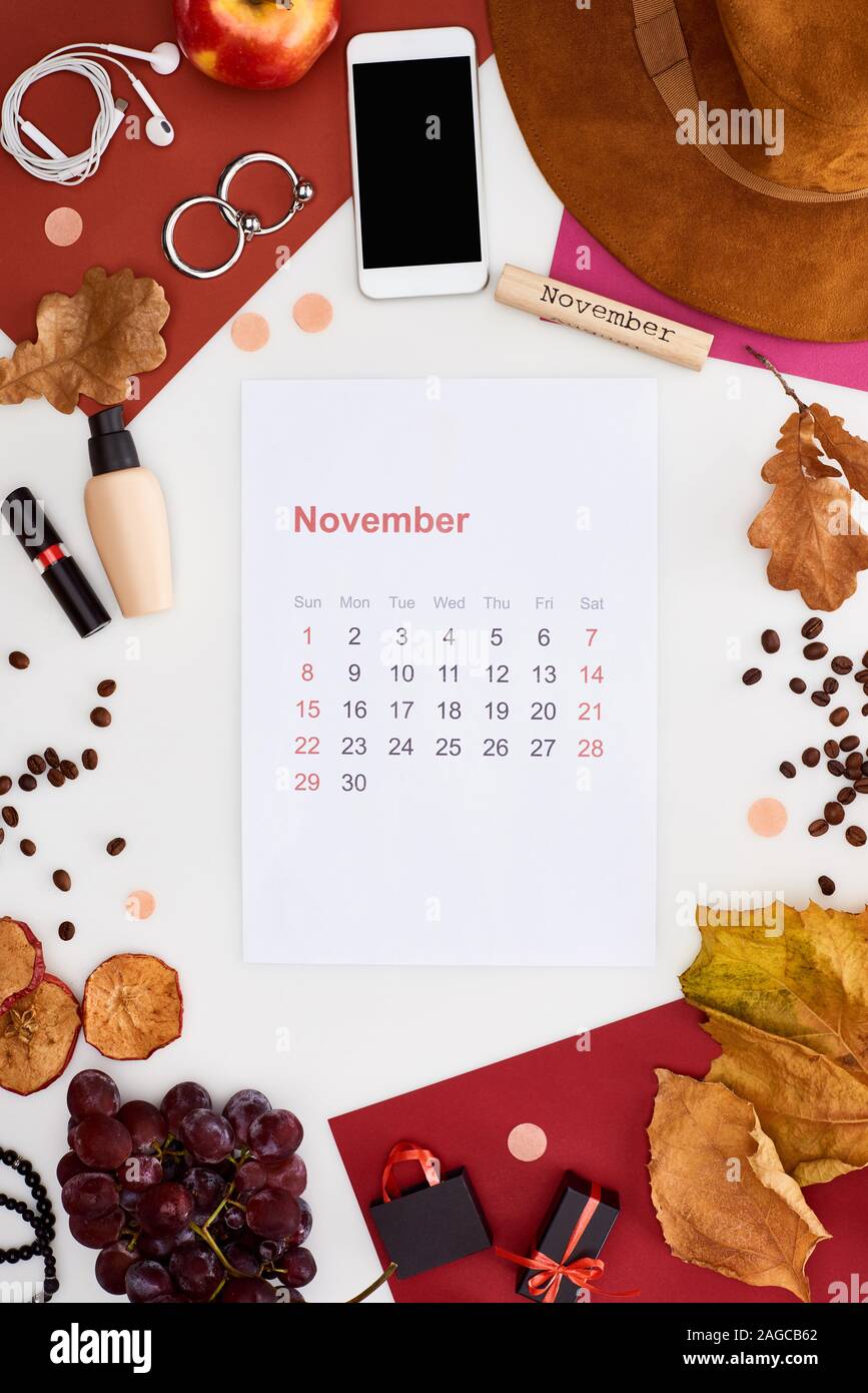 november calendar page near hat, dry leaves, fruits, donut, cosmetics ...