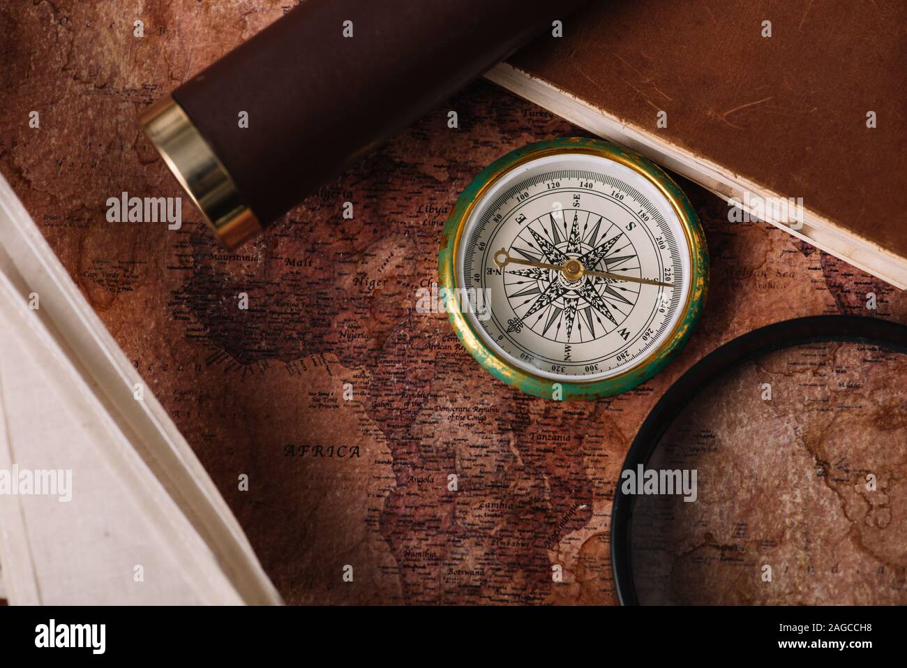 top view of compass near copy book and magnifying glass on old world ...