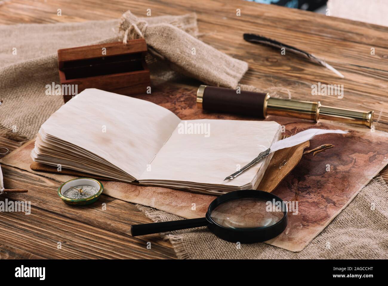 open copy book with blank pages near telescope, compass and magnifying ...