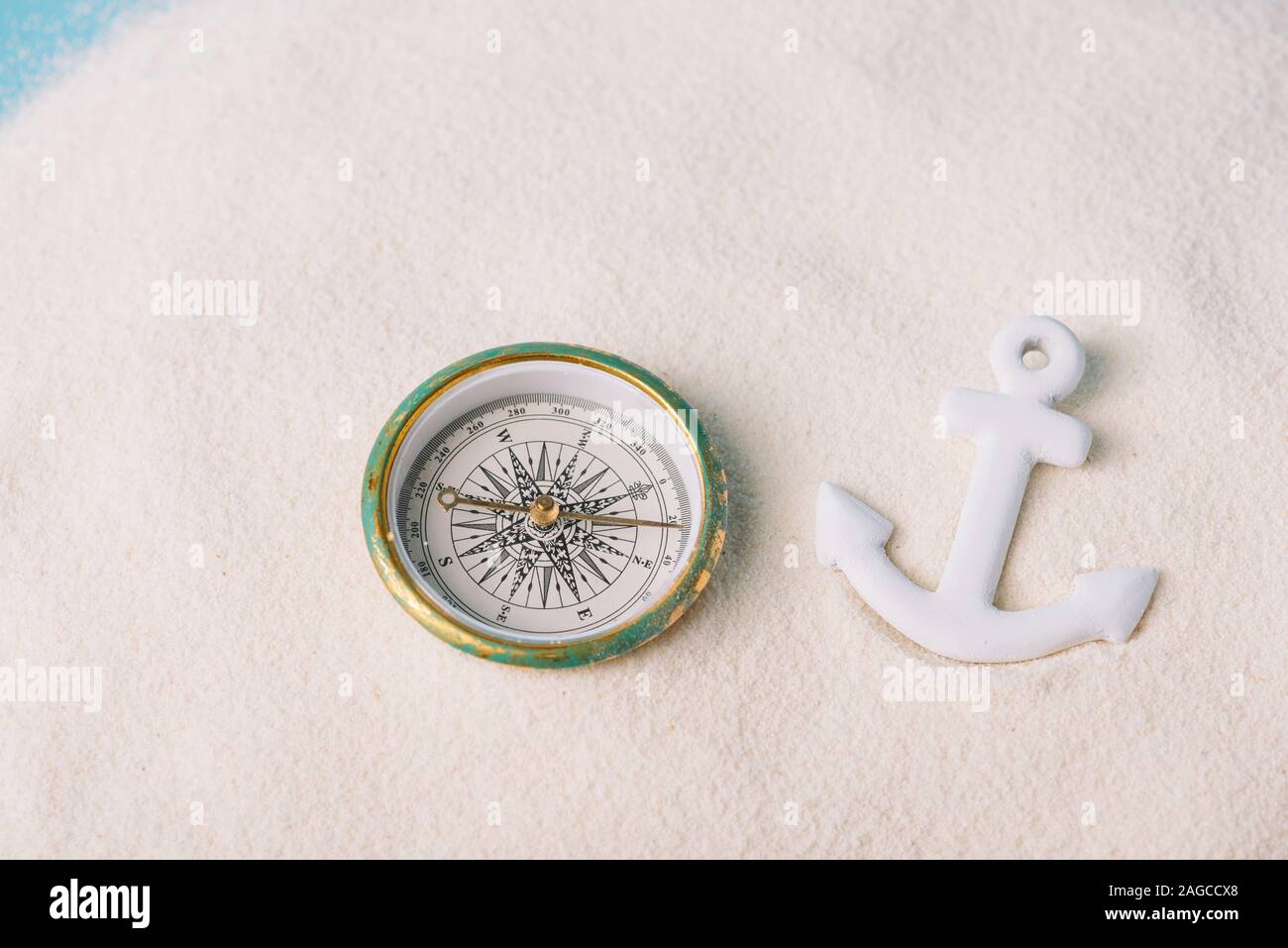 compass and plastic anchor on white sand Stock Photo - Alamy