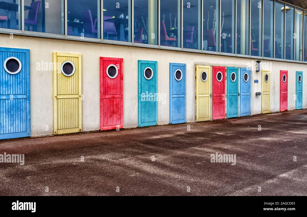 Outdoor hallway with doors of different colors with a nice modern cafe ...