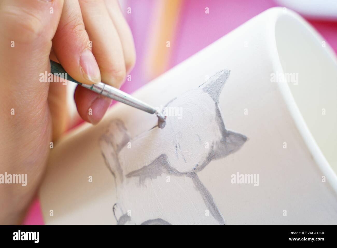 Child paints a mug in a pottery workshop. Drawing a cat Stock Photo - Alamy