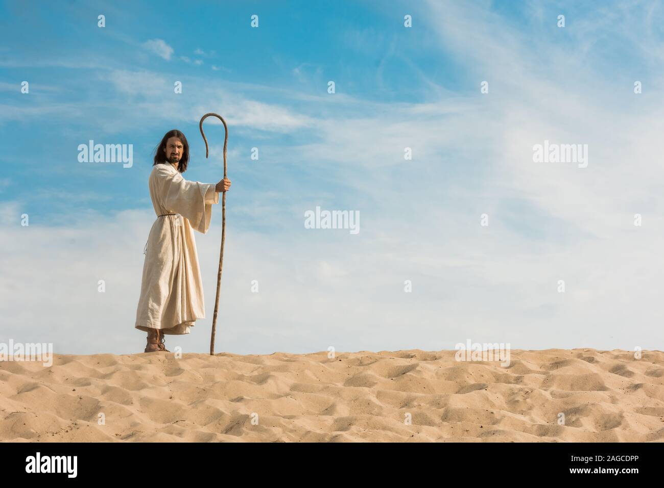 jesus holding wooden cane against blue sky in desert Stock Photo - Alamy