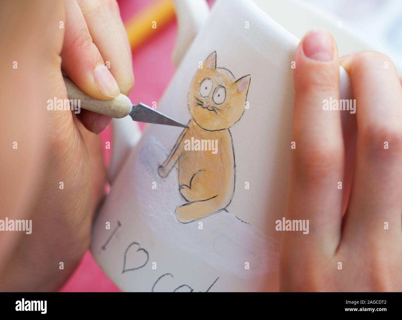 Child paints a mug in a pottery workshop. Drawing a cat Stock Photo - Alamy