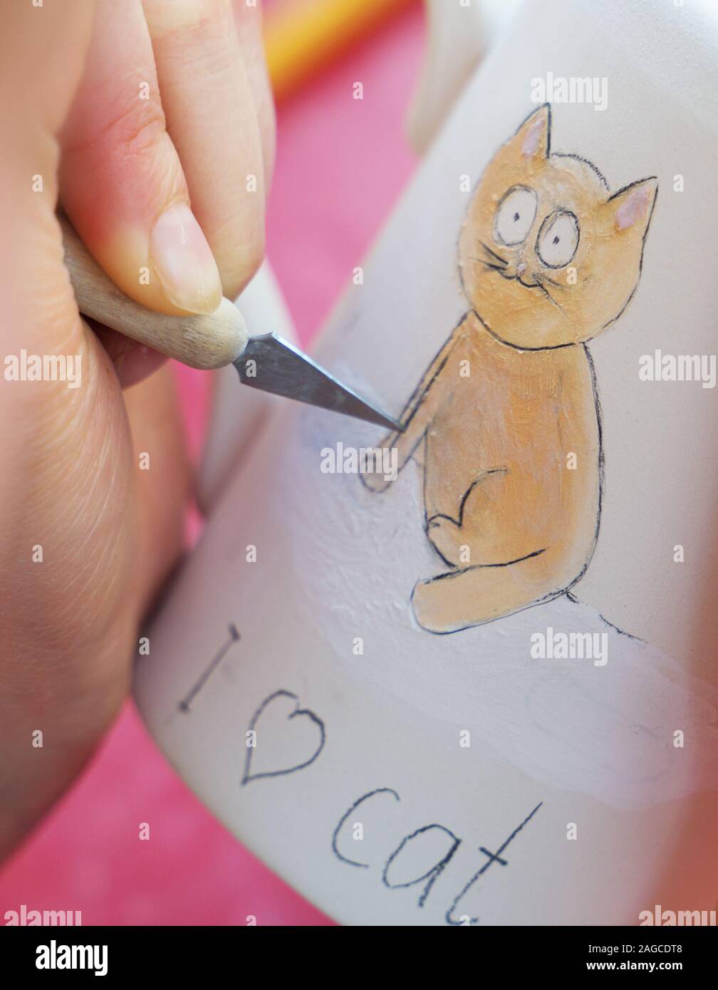 Child paints a mug in a pottery workshop. Drawing a cat Stock Photo - Alamy