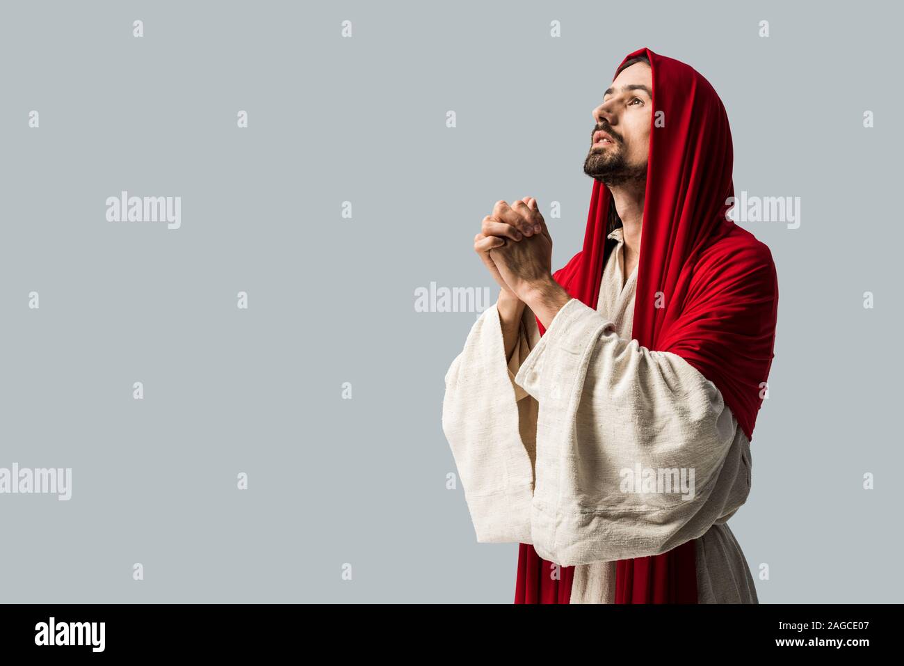 handsome man in red hood praying isolated on grey Stock Photo - Alamy