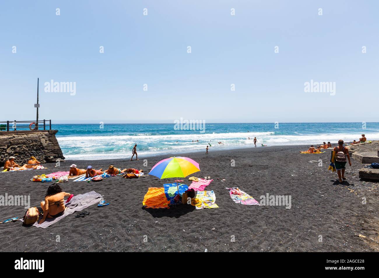 typical tenerife beach with black volcanic sand, sunbathing and ...