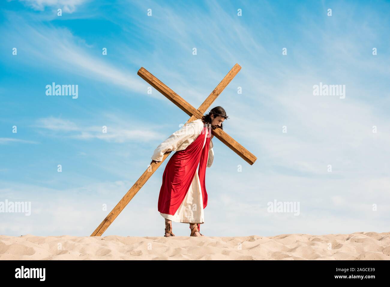 bearded man in jesus robe walking with wooden cross against sky in ...