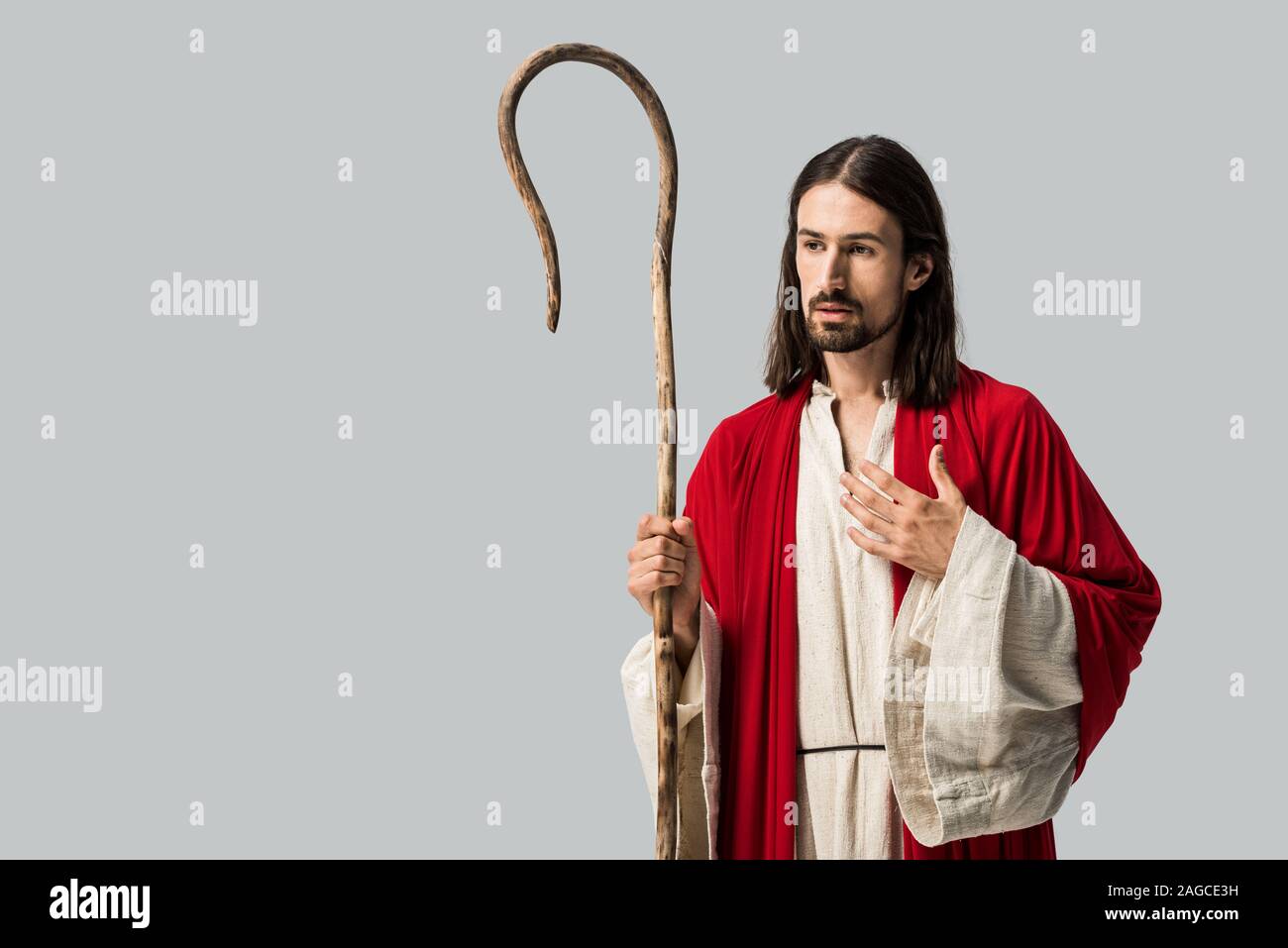 bearded man in jesus robe holding wooden cane while putting hand on ...