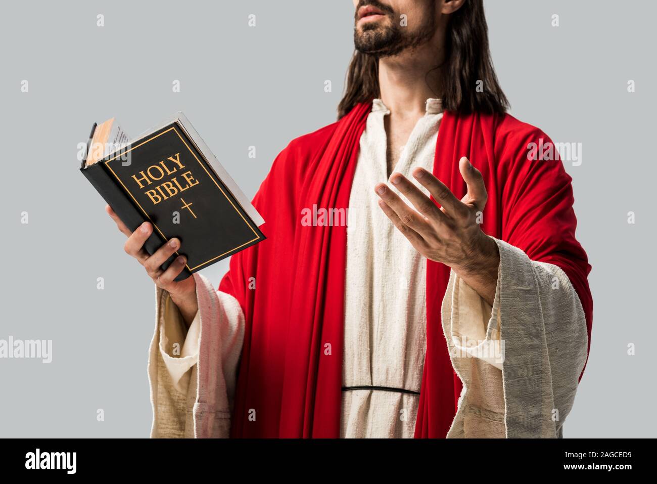 cropped view of religious man in jesus robe holding holy bible and ...