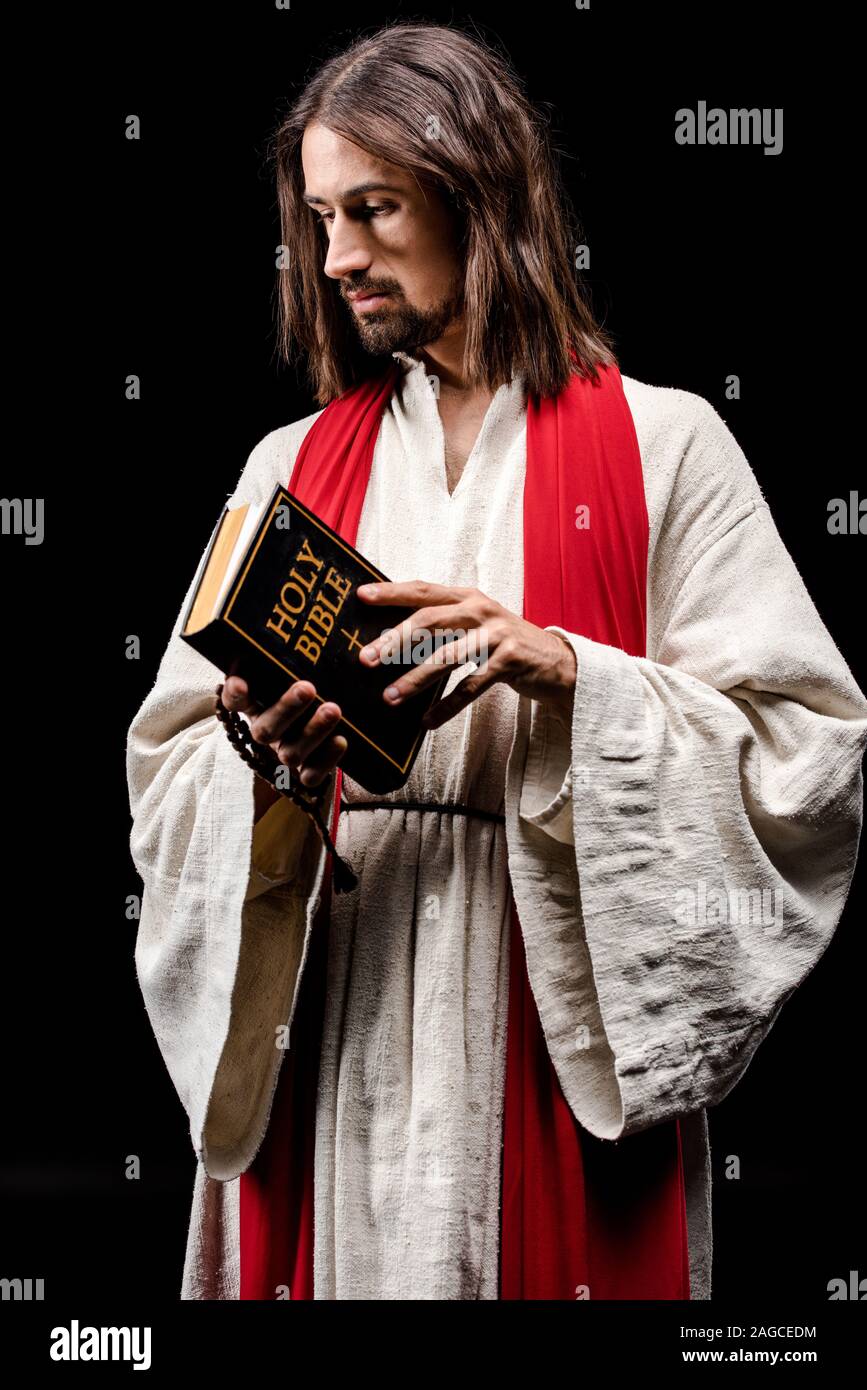 religious man in jesus robe holding holy bible isolated on black Stock ...