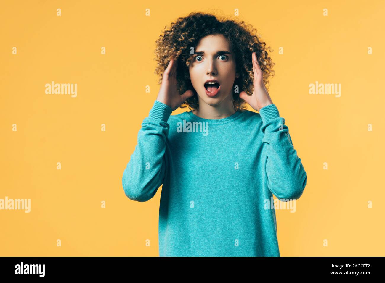 scared curly teenager with open mouth isolated on yellow Stock Photo ...
