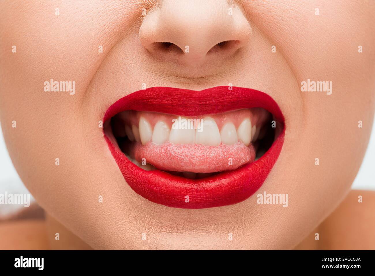cropped view of woman with red lips sticking out tongue isolated on ...