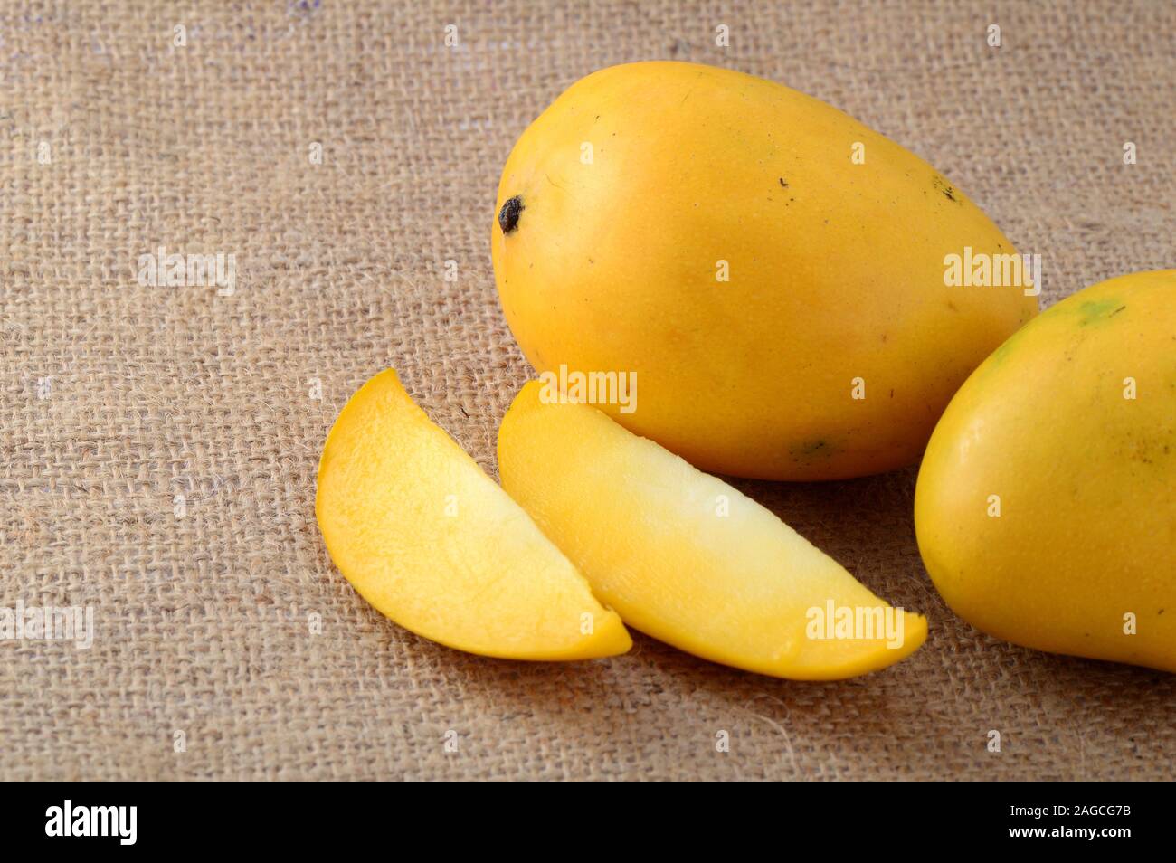 Mango fruit with slice on sack cloth background Stock Photo - Alamy