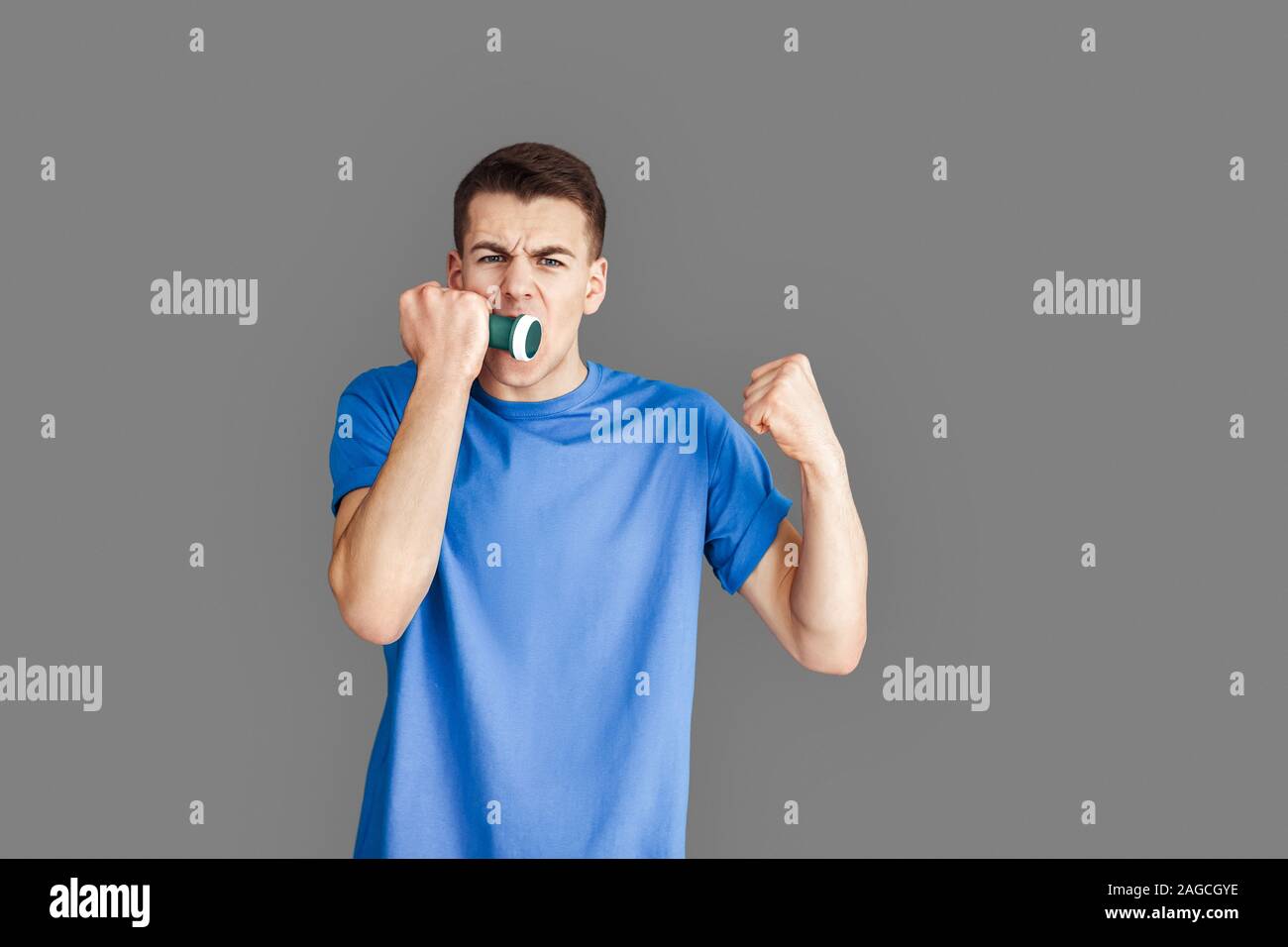 Freestyle. Young man standing isolated on grey making sound with noise ...