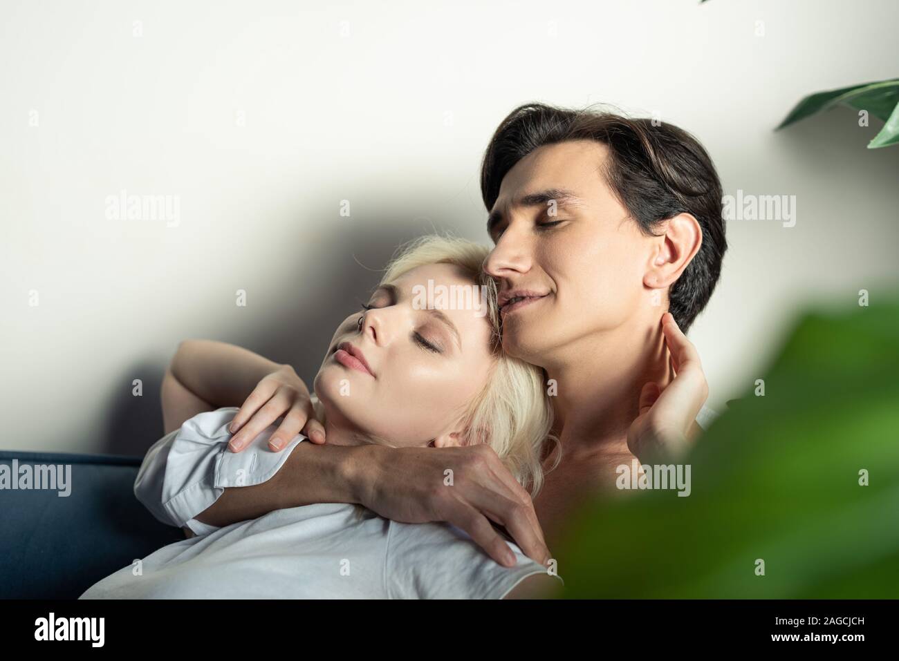 Side view of smiling couple with closed eyes embracing at home Stock ...