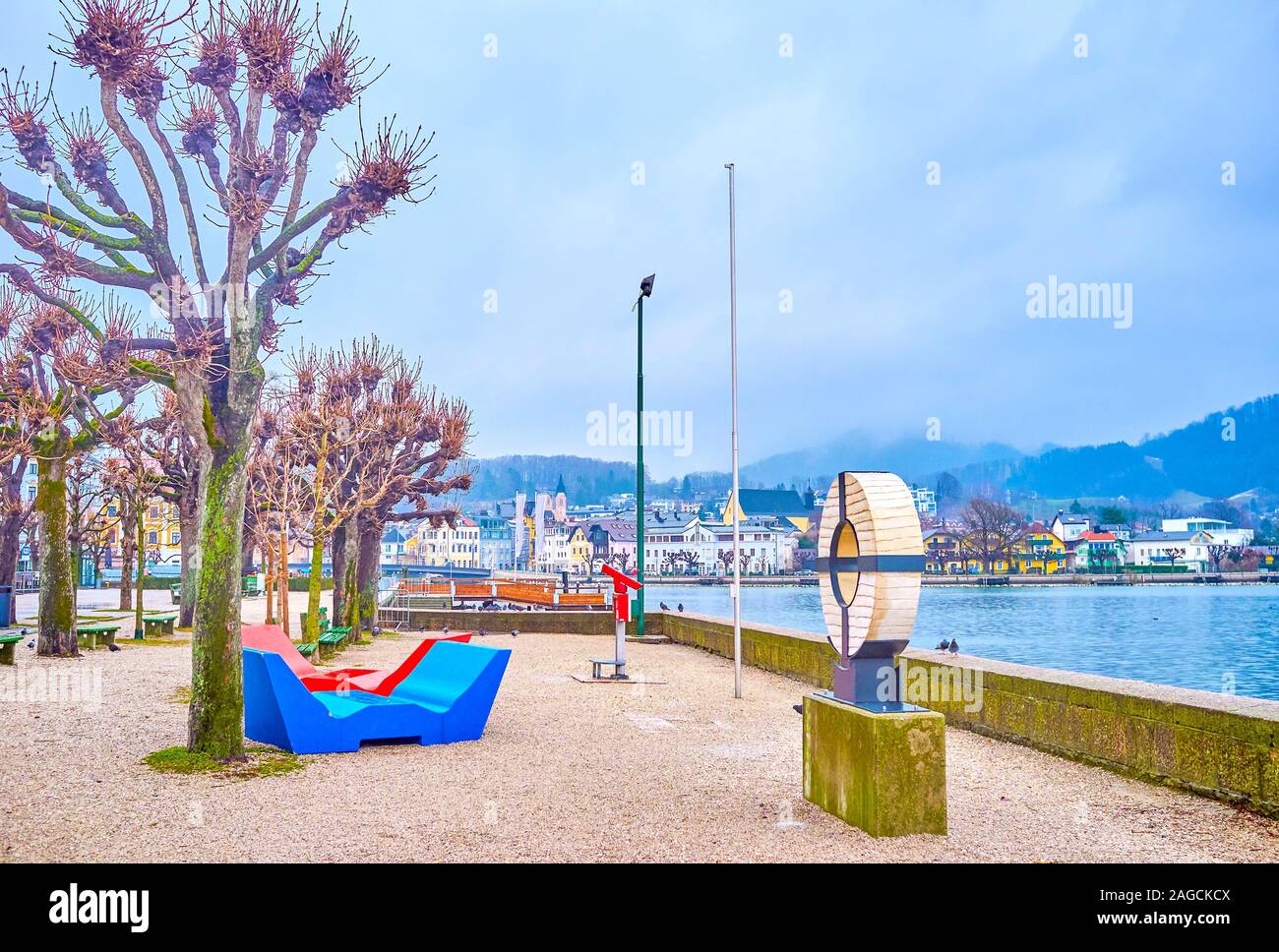 The pleasant promenade of Traun lake (Traunsee) with trimmed trees ...
