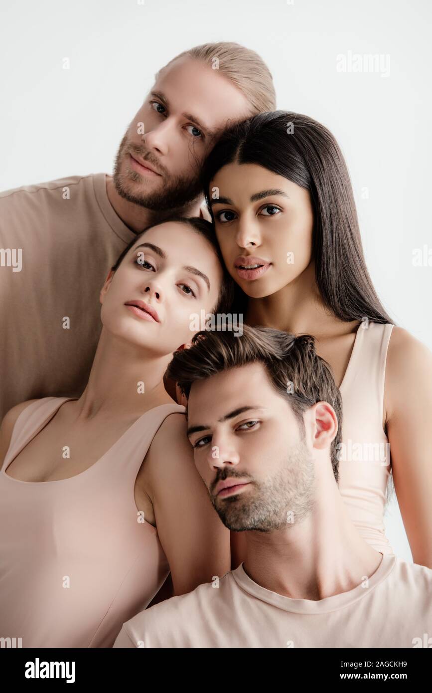 young multicultural men and women in beige outfit posing together ...