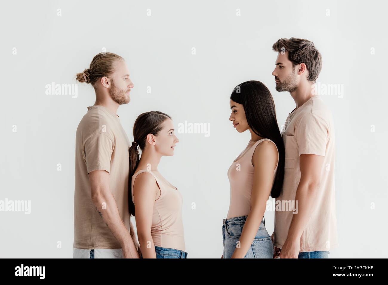 side view of young multicultural men and women in beige outfit standing ...