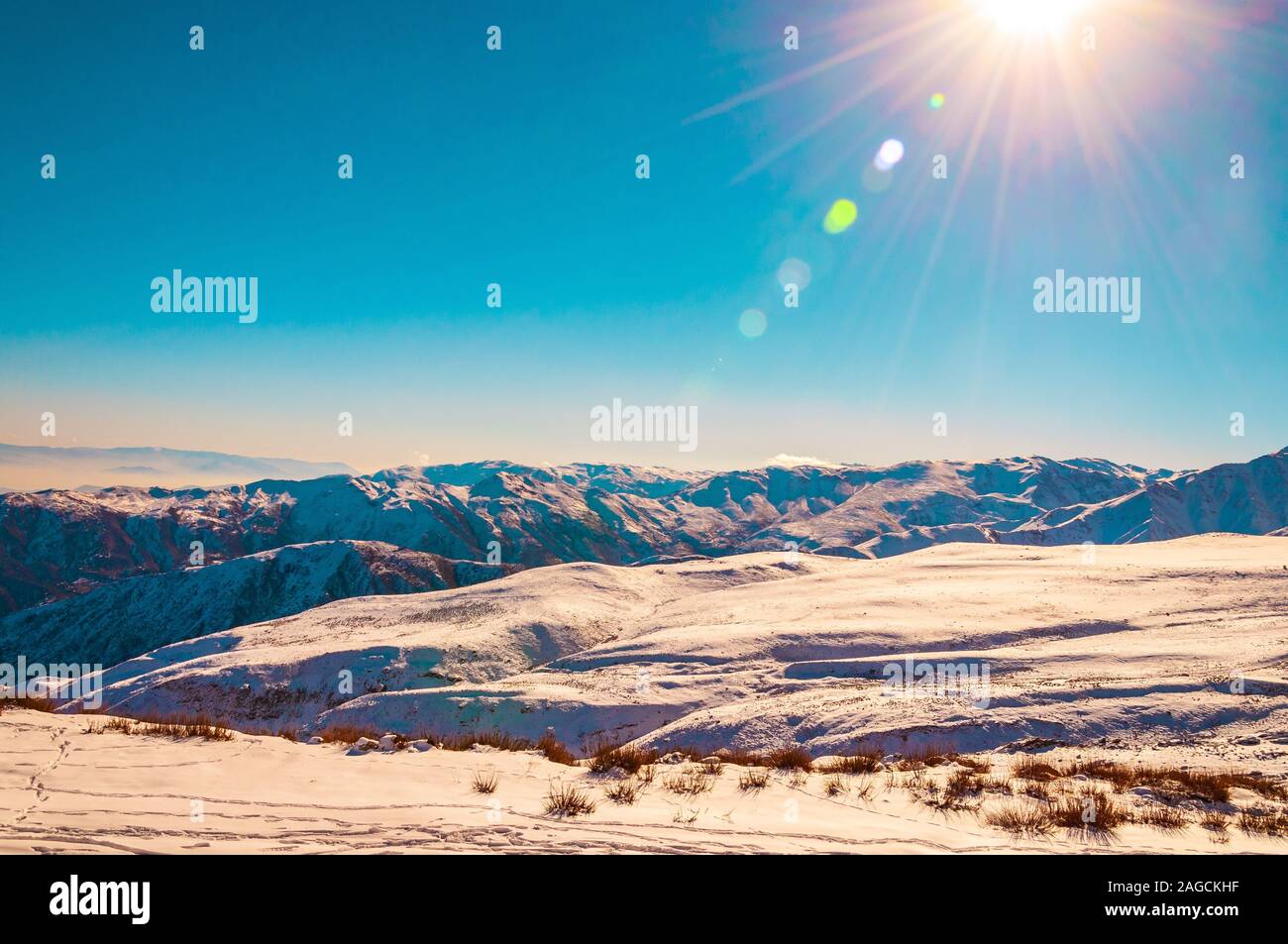 Beautiful low angle shot of the sun rising over the snowy mountains in ...